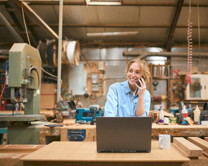 Female Carpenter Working in Woodwork Workshop Talking on Mobile Phone ...