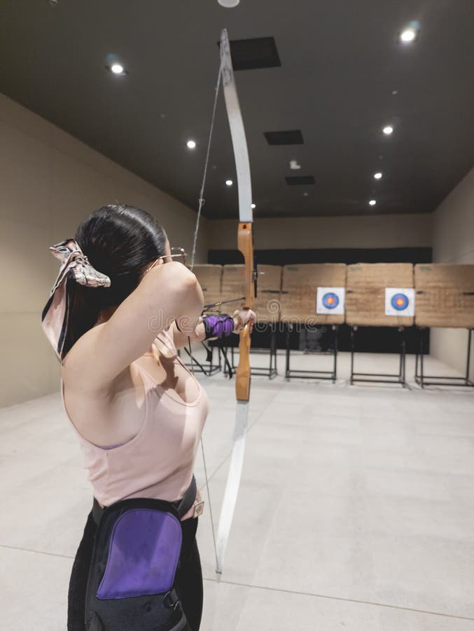 A Female Casual Hobbyist Doing Target Practice at an Indoor Archery Range Stock Photo - Image of ...