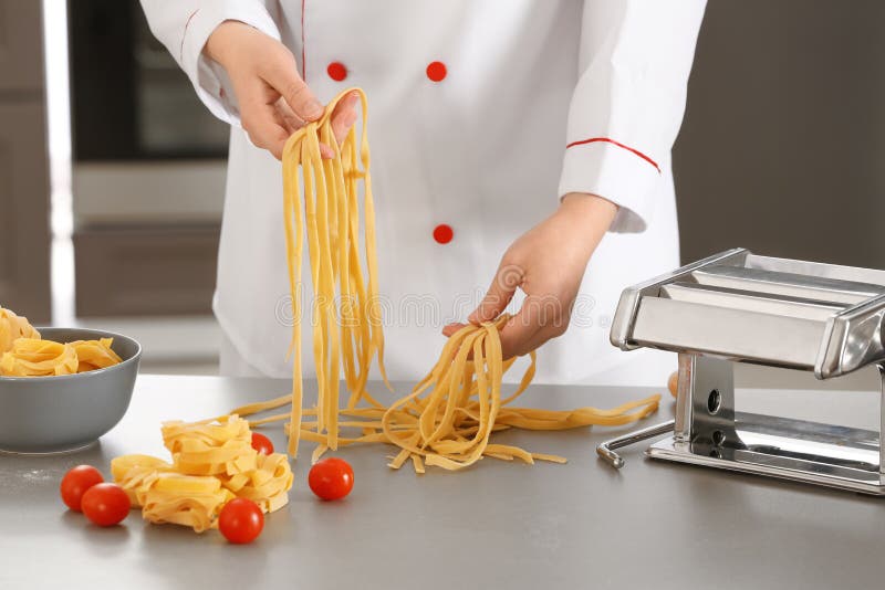 Female Chef Preparing Pasta at Table Stock Photo - Image of machine ...