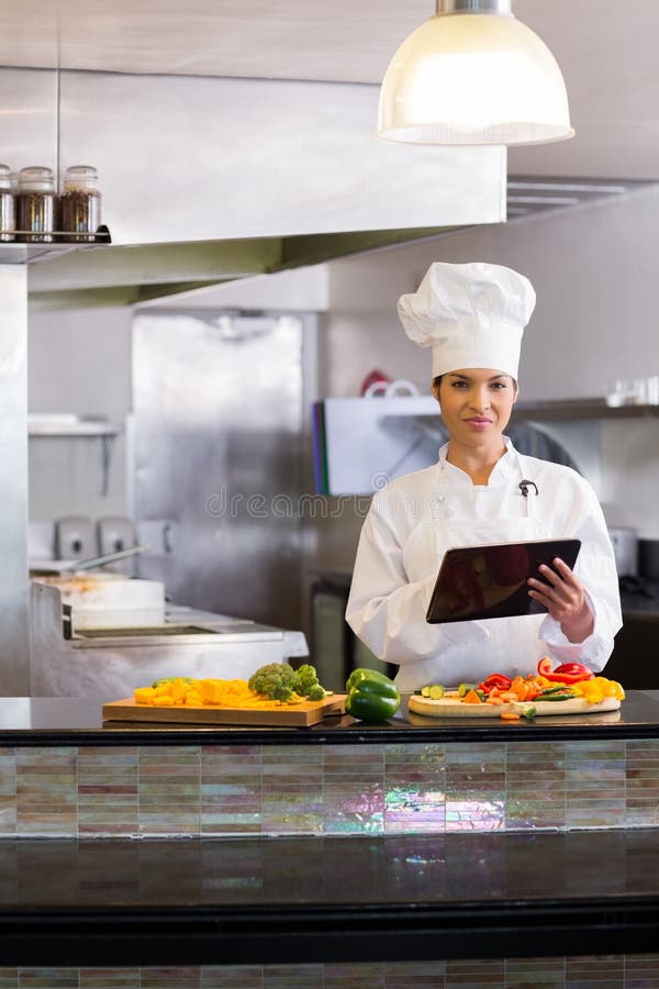 Female Chef Using Digital Tablet while Cutting Vegetables in Kitchen ...