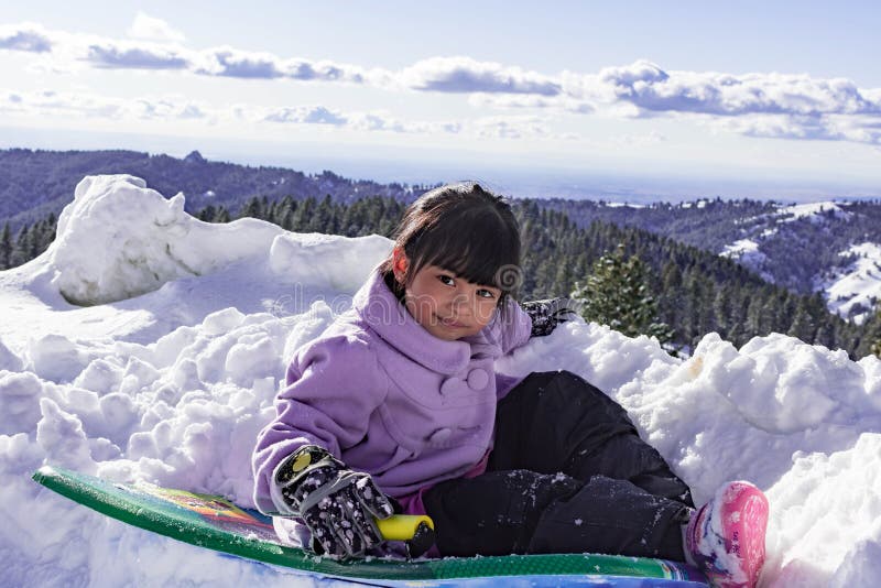 Female Child while Sitting on a Snow Board and Playing with Snow Stock ...