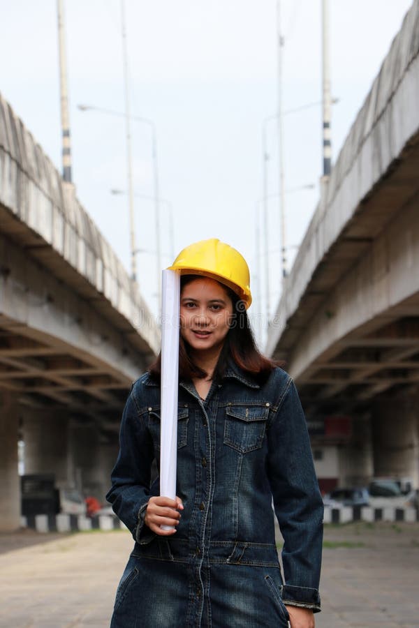 Female Civil Engineer with Yellow Helmet, Standing with Project Drafts ...