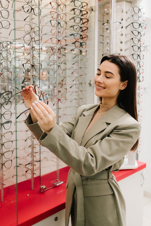 Female Client Chooses Eyeglasses from the Stand in the Optical Store ...