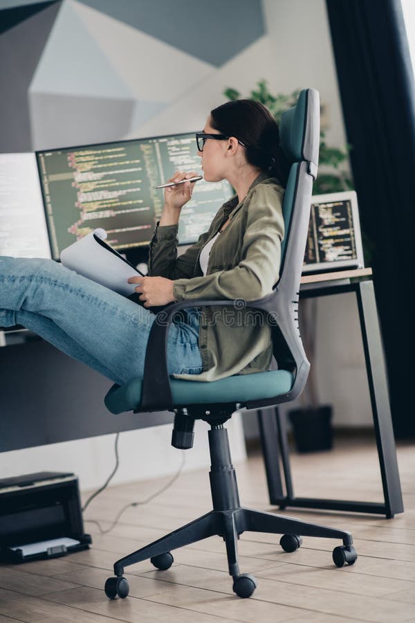 Young Woman Programmer Analyzing Code on Dual Monitors in a Modern ...