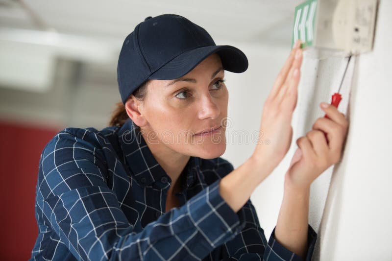 Female Contractor Installing Illuminated Exit Sign Stock Photo - Image ...