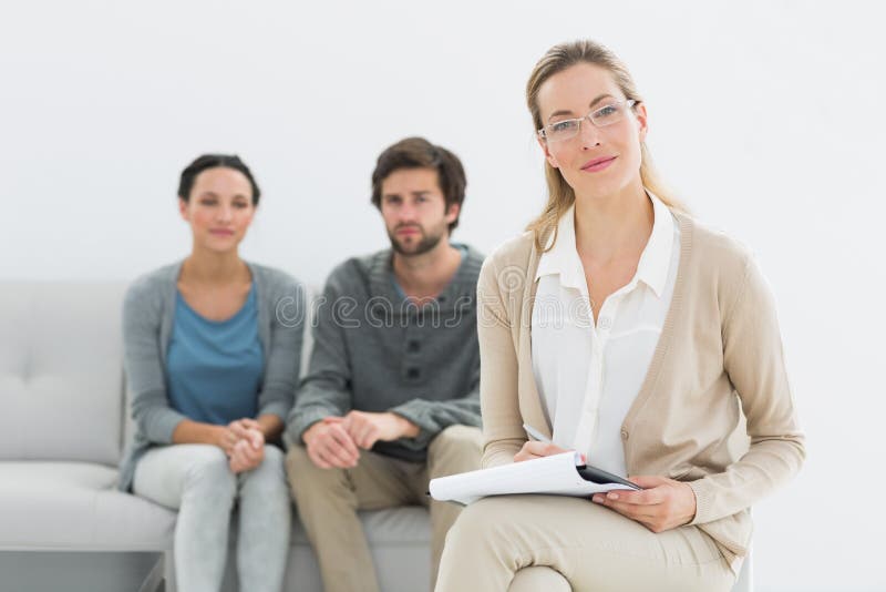 Female Counselor with Young Couple in Background Stock Photo - Image of ...