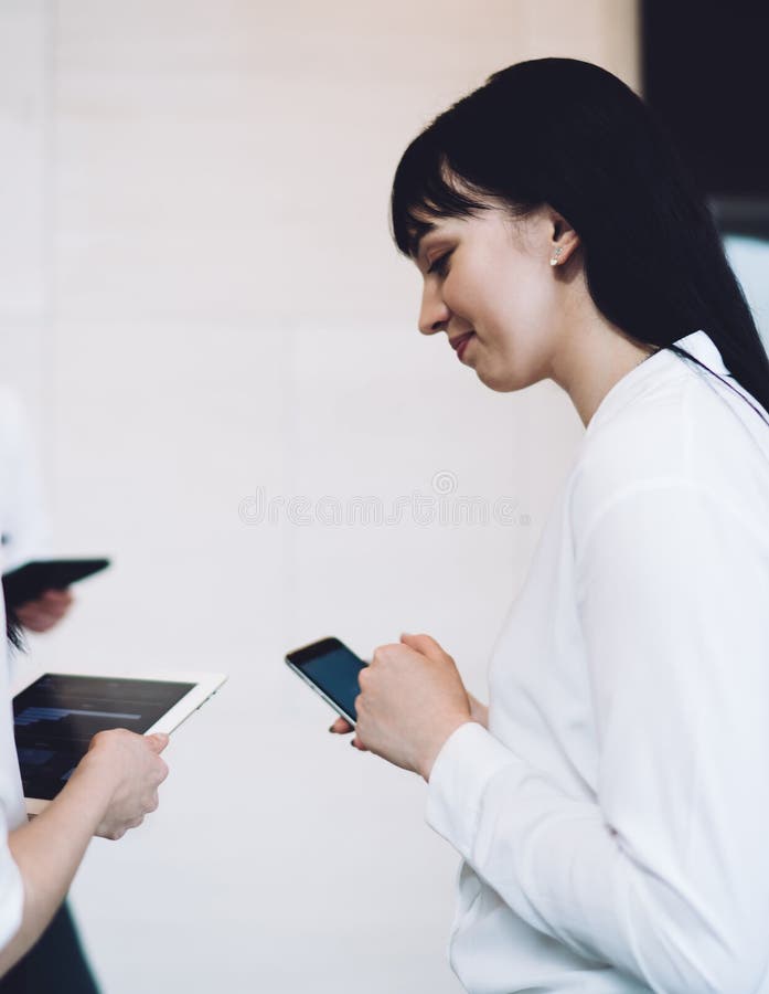 Female Coworkers Talking while Using Gadgets Stock Photo - Image of ...