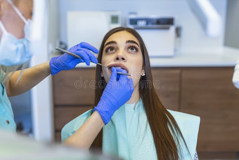 Female Dentist Treating Teeth To Patient Young Woman In Chair At