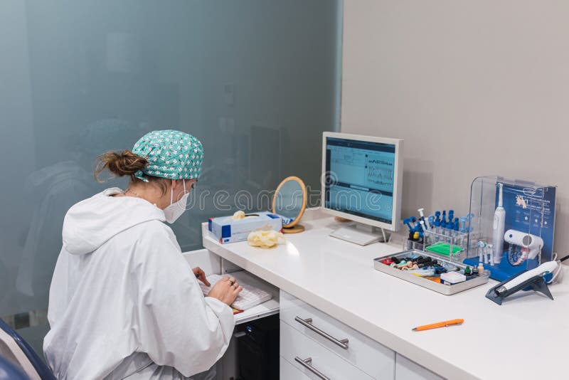 Female Dentist Using Computer at Office Desk. Looking at the Screen ...