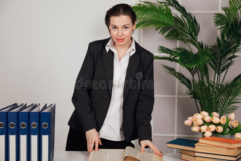The Female Director in the Office Stands at the Desk with the Book in ...