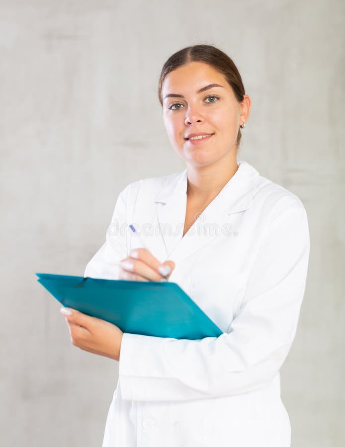 Female Doctor Makes Notes in Documents Holding a Folder of Papers in ...