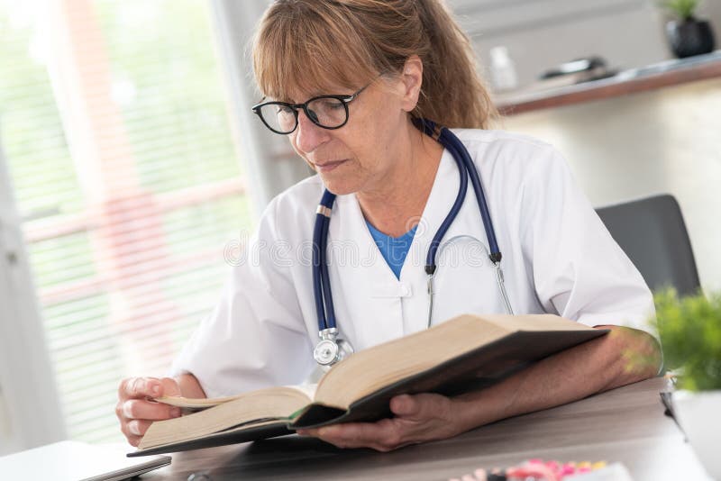 Female Doctor Reading a Textbook Stock Image - Image of woman, care ...
