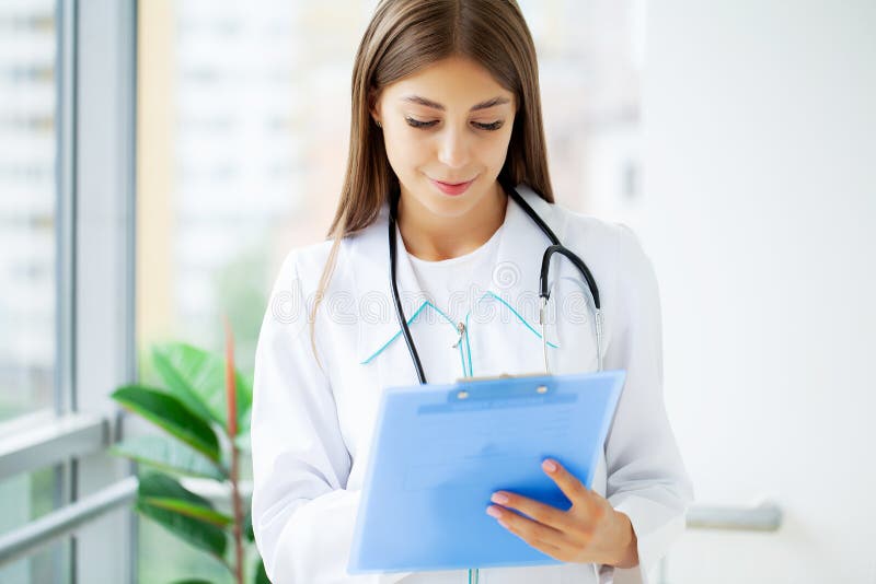 Female Doctor in Surgery Reading Patient Notes Stock Image - Image of ...