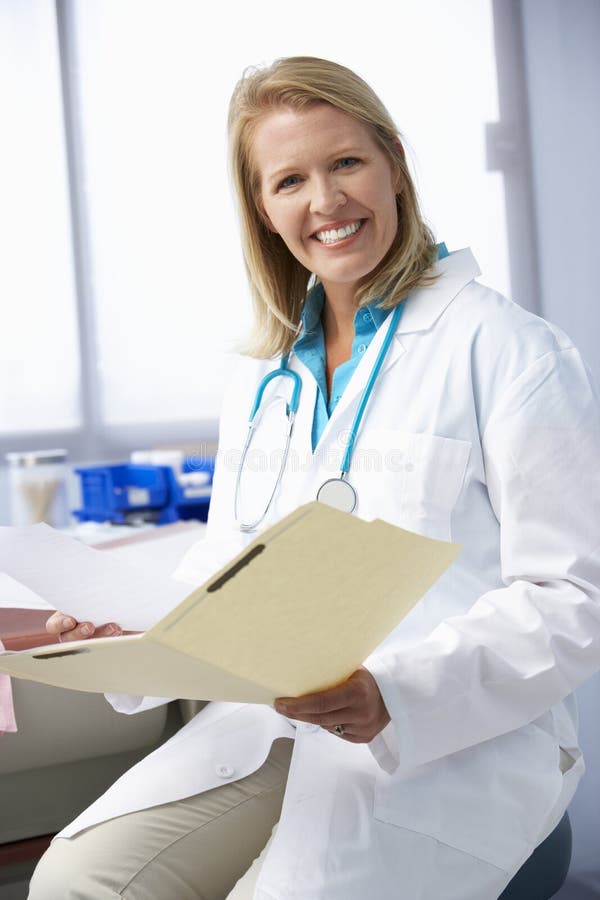 Female Doctor in Surgery Reading Patient Notes Stock Photo - Image of ...