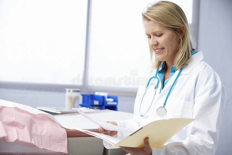 Female Doctor in Surgery Reading Patient Notes Stock Image - Image of ...