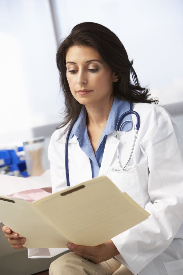 Female Doctor in Surgery Reading Patient Notes Stock Image - Image of ...