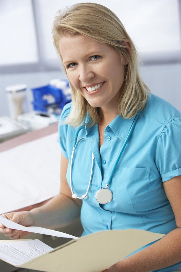 Female Doctor in Surgery Reading Patient Notes Stock Image - Image of ...