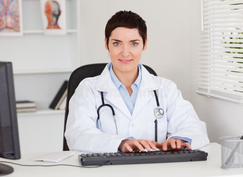 Female Doctor Sat at Desk Using Computer Stock Photo - Image of ...
