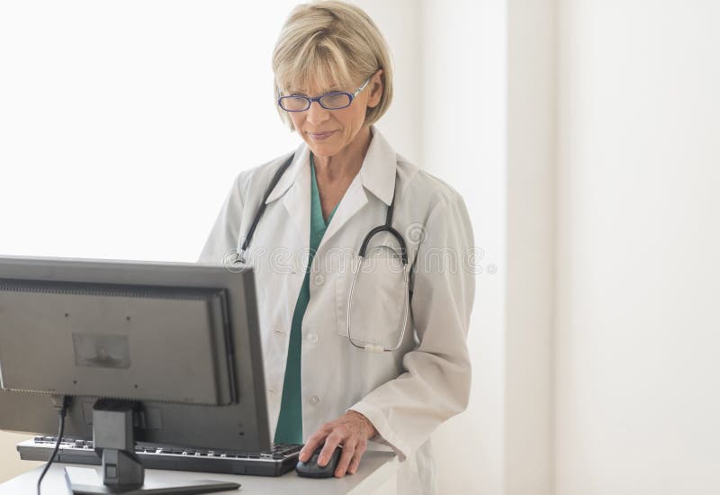 Female Doctor Using Desktop PC at Desk Stock Photo - Image of beautiful ...