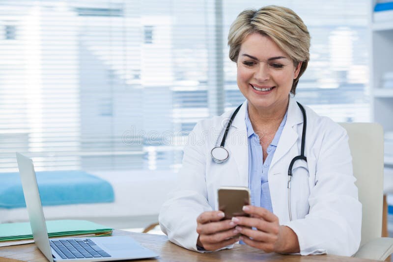 Female Doctor Using Mobile Phone with Laptop on Table Stock Photo ...