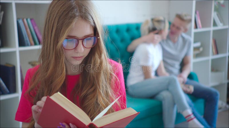 Female Dork is Reading Tutorial while Couple Hugging on the Couch at ...