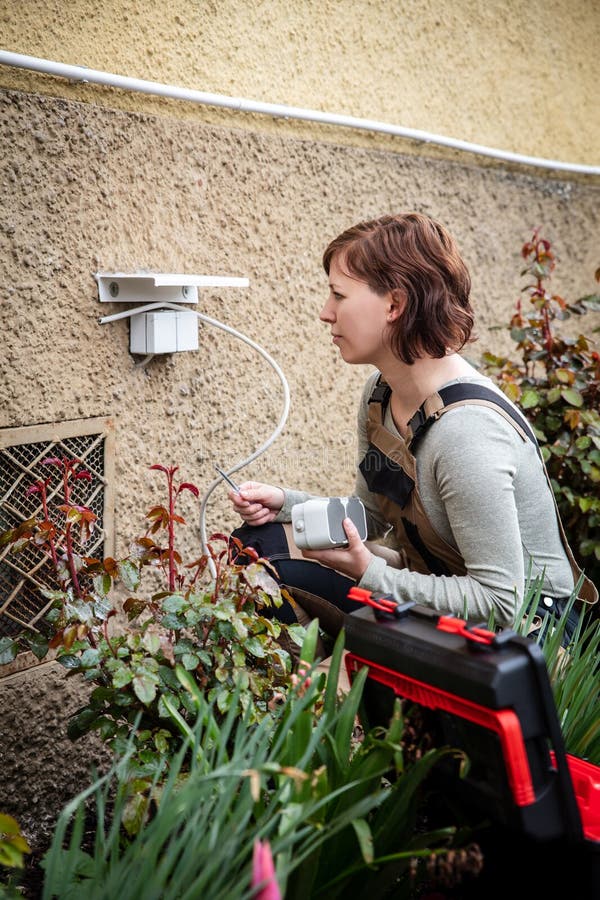 Female Electrician Installs a Socket Outside in the Garden Stock Photo ...