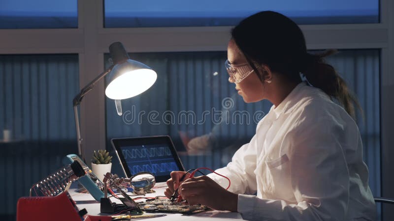 Female Electronics Engineer Working with Multimeter Tester and Other ...