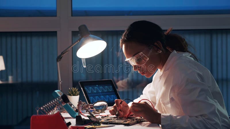 Female Electronics Engineer Working with Multimeter Tester and Other ...