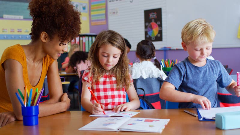 Female Elementary School Teacher Giving Female Pupil One To One Support ...