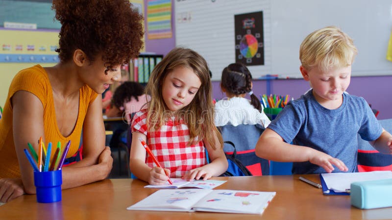 Female Elementary School Teacher Giving Female Pupil One To One Support ...