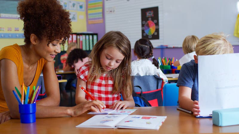 Female Elementary School Teacher Giving Female Pupil One To One Support ...