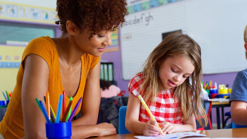 Female Elementary School Teacher Giving Female Pupil One To One Support ...