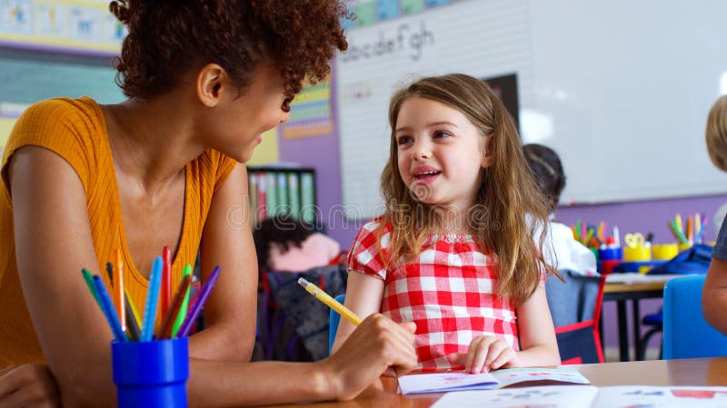 Female Elementary School Teacher Giving Female Pupil One To One Support ...