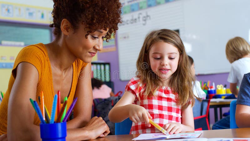 Female Elementary School Teacher Giving Female Pupil One To One Support in Classroom Stock Photo ...