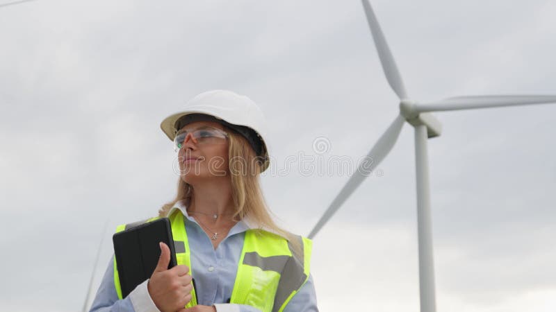 A Female Engineer with a Digital Tablet Analyzes Data from Wind Energy ...