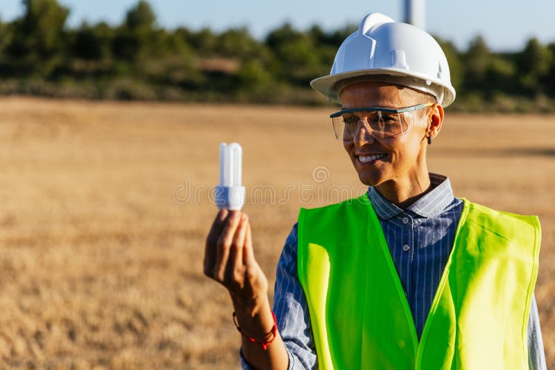 Female Engineer Holding a Light Bulb while Standing Outdoors in the ...
