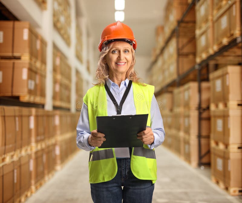 Female Engineer with a Safety Vest and Hardhat Standing in a Warehouse ...