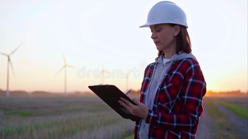 Female Engineer Taking Notes on a Clipboard on a Field with Wind ...