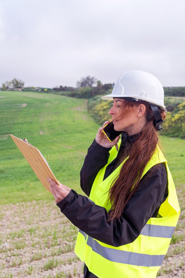 Female Engineer Using Smartphone and Clipboard in Green Field Stock ...