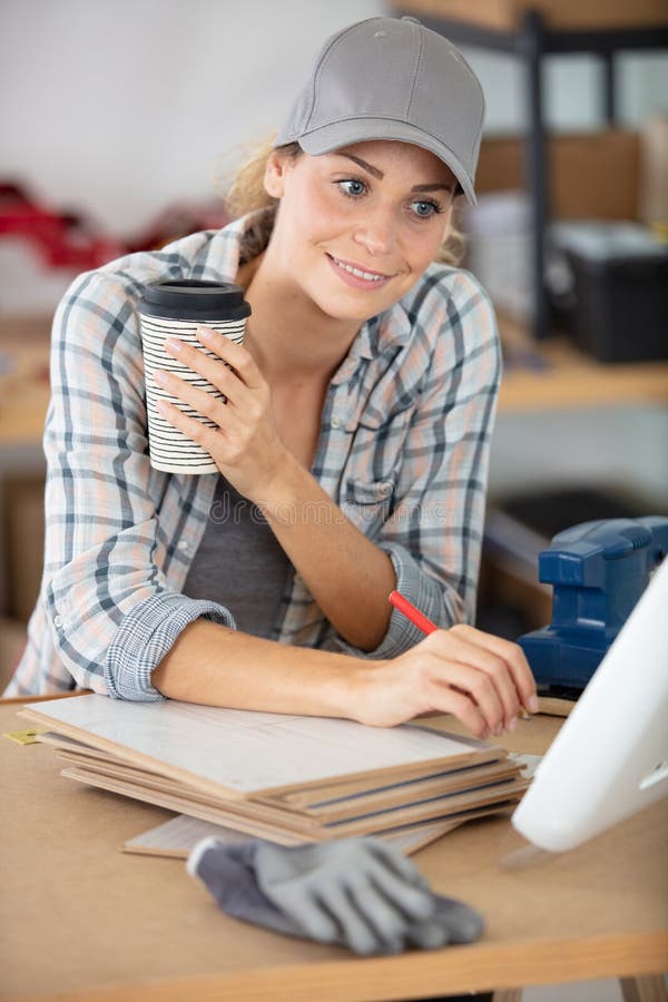 Female Engineer Wearing Cap Sits at Desk Holding Coffee Stock Photo ...