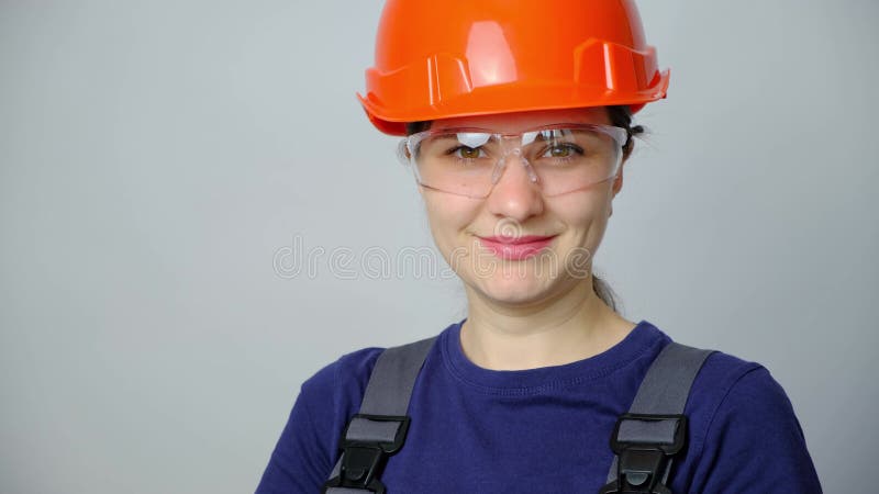 A Female Engineer in Work Overalls and a Helmet Wears Goggles on a ...