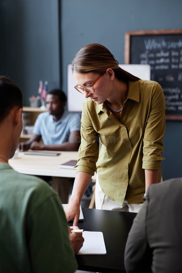 Female English Instructor Helping Student with Task in Class at School ...