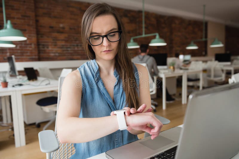 Female Executive Adjusting Smart Watch at Desk Stock Image - Image of ...