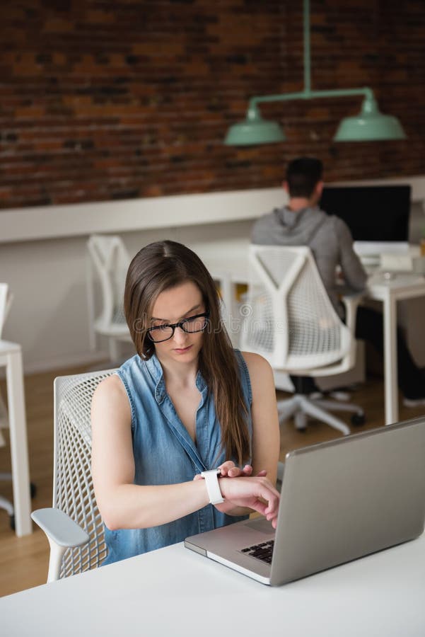 Female Executive Adjusting Smart Watch at Desk Stock Photo - Image of ...