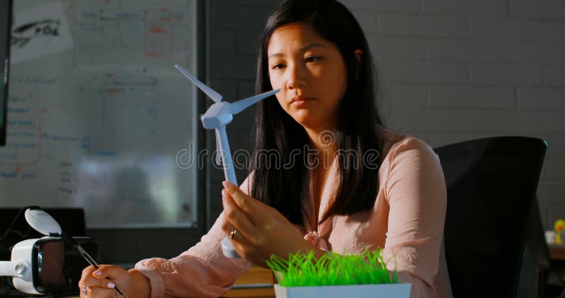 Female Executive Examining a Windmill Model in Office Stock Photo ...