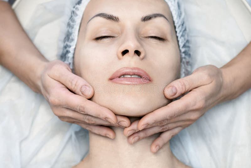 Female Face With Closed Eyes And Disposable Cap Masseurs Hands Touch