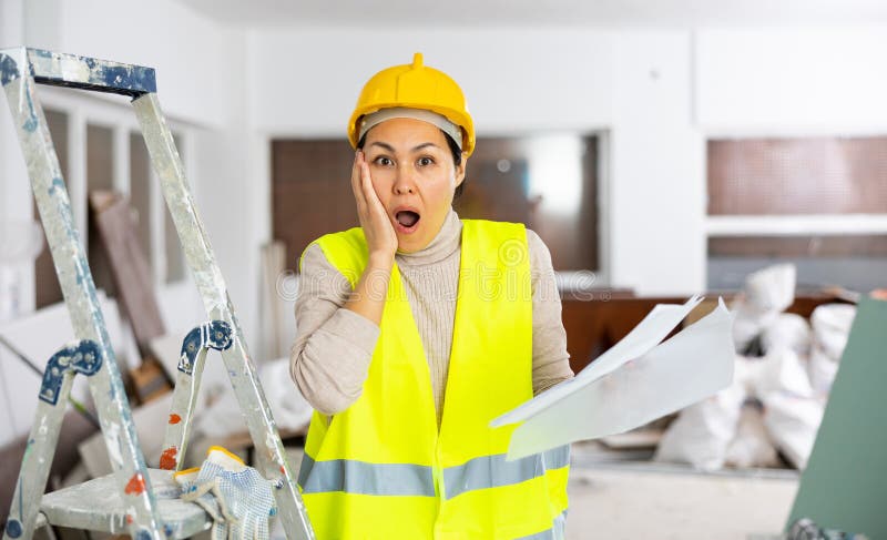 Female Foreman in a Protective Helmet and a Yellow Vest Checks the ...