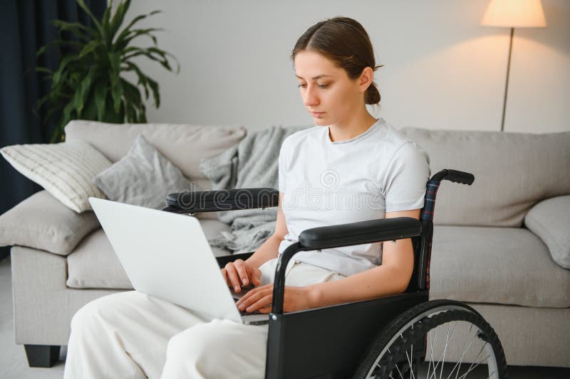 Female Freelance Programmer Sitting in Wheelchair and Using Computers while Coding Web Game at ...