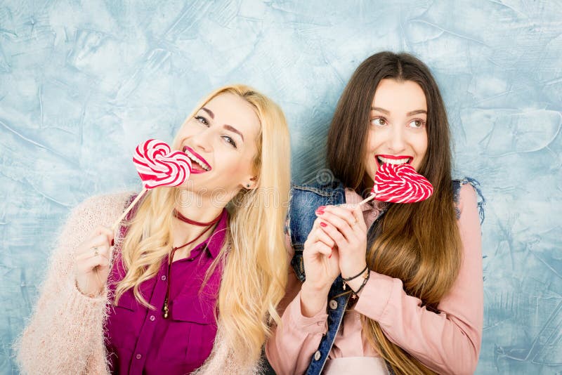 Female Friends with Candy on the Blue Background Stock Image - Image of ...