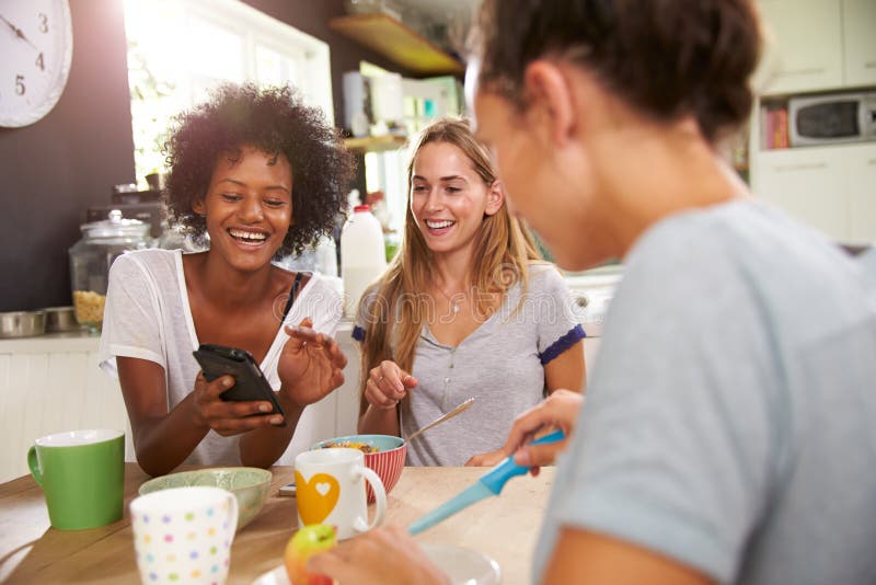 Female Friends Eating Breakfast Whilst Checking Mobile Phone Stock ...